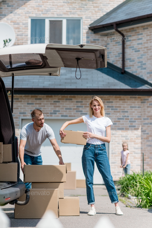 couple carrying cardboard boxes for relocation into new house and their ...