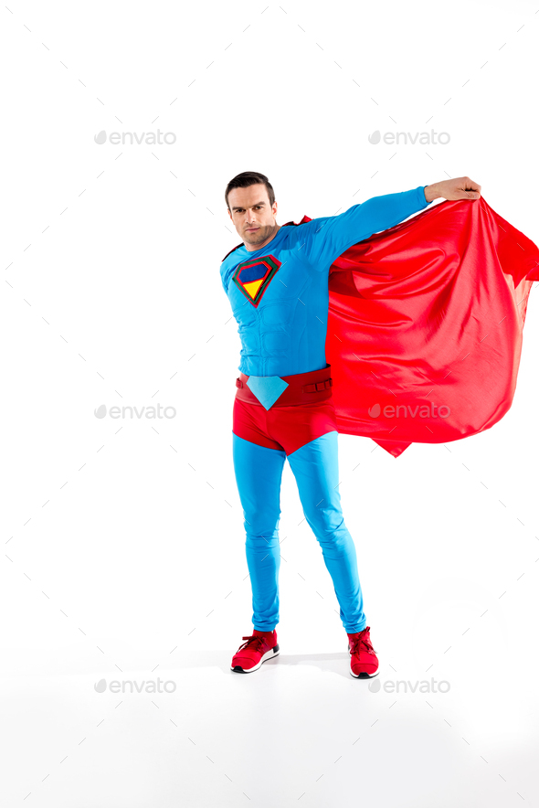 handsome man in superhero costume and cloak looking at camera isolated ...