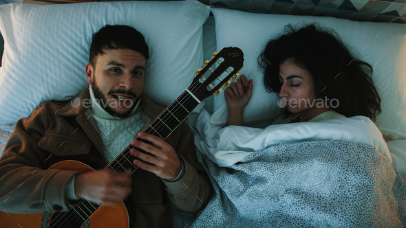 Man sing and Play the guitar in a bad Stock Photo by francescosgura