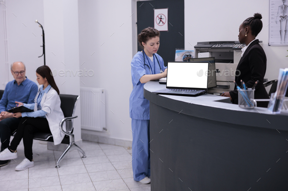 Reception worker talking with assistant discussing medical report ...