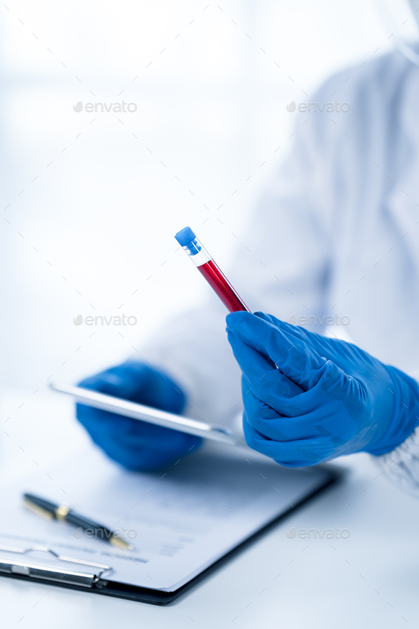 Doctor hand taking a blood sample tube from a rack with machines of ...