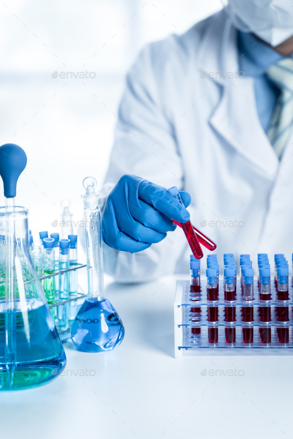 Doctor hand taking a blood sample tube from a rack with machines of ...