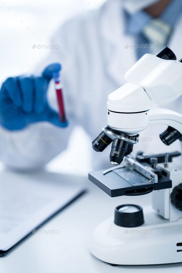 Doctor hand taking a blood sample tube from a rack with machines of ...