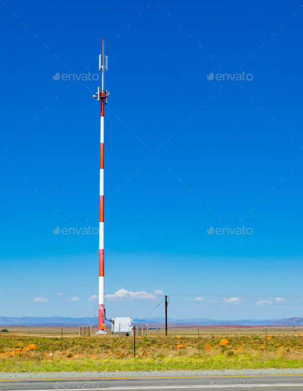 Vertical shot of a red and white cellphone Tower in the countryside of ...