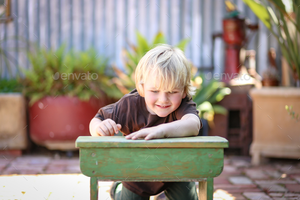 Happy adorable blonde Australian kid sitting and leaning on a small ...