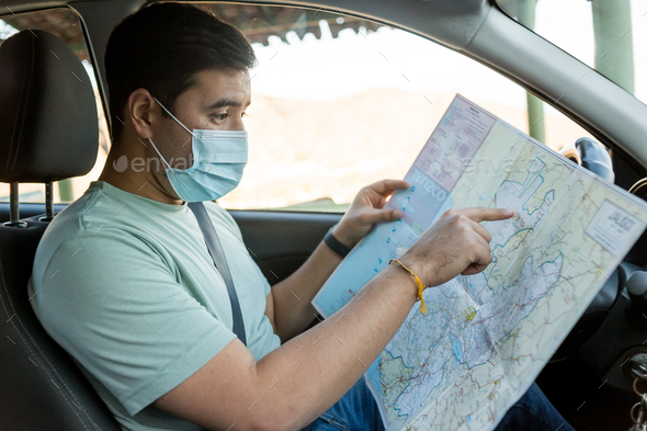 Male traveler wearing a sanitary mask sitting in his car showing the ...