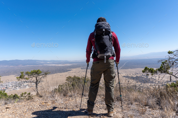 Back view of a male hiker standing on top of a hill enjoying beautiful ...