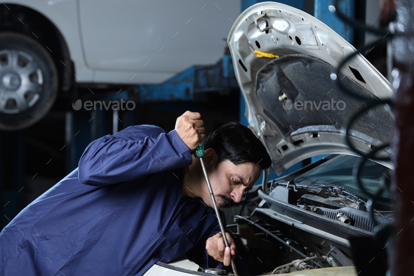 Portrait of a handsome mechanic working on a car in a car service Stock ...