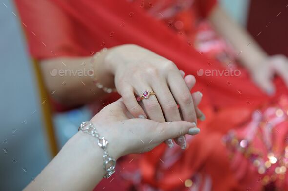 Girl in red holds her friend's hand showing her ring Stock Photo by ...