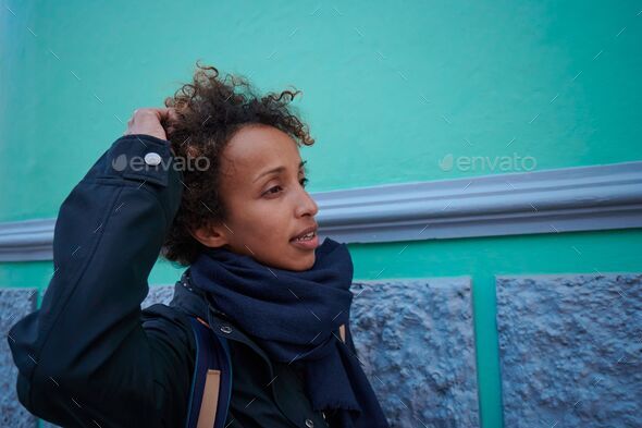 Mature African American woman scratching her head in front of a green ...