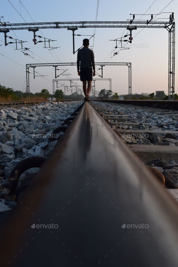Vertical shot of a guy walking alone of a train railroad in the ...