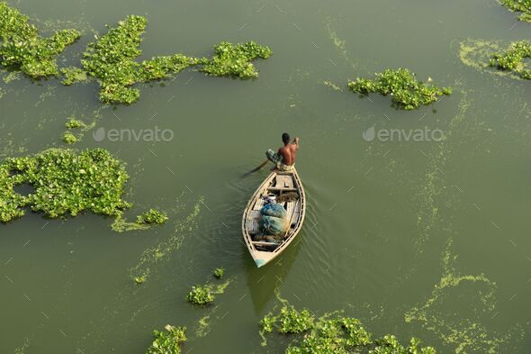 Bird's eye view of a fisherman rowing a small wooden boat on the ...