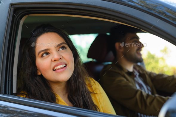 Shallow focus of a young happy Hispanic couple driving a car under the ...