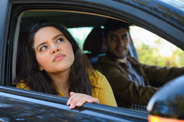 Shallow focus of a young Hispanic couple driving a car under the ...