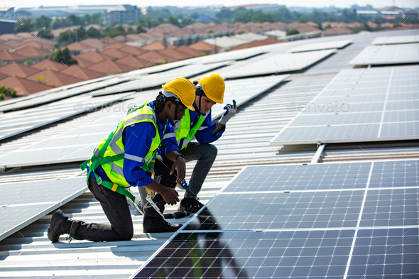 Solar panel installer installing solar panels on roof of warehouse ...