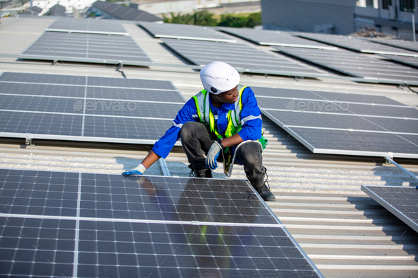 Solar panel installer installing solar panels on roof of warehouse ...
