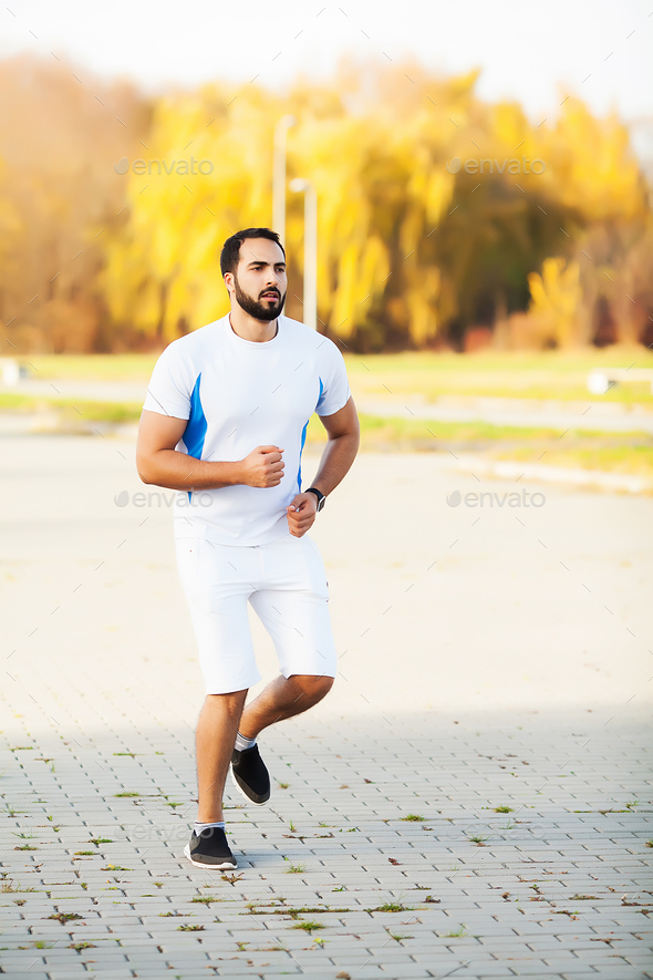 Fit muscular man running and doing exercise outside Stock Photo by maksymiv