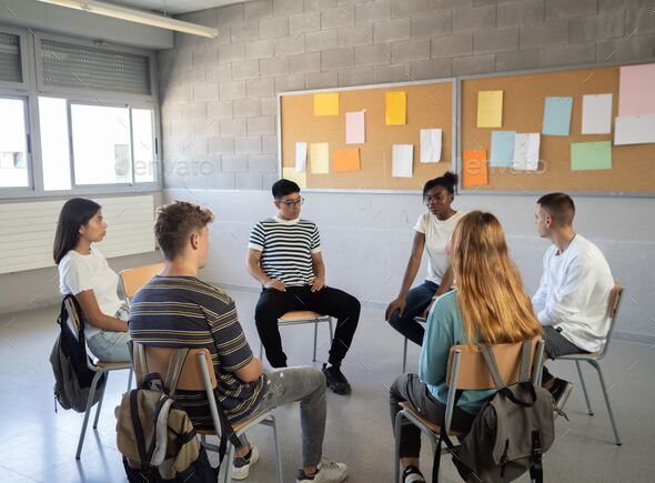 Group of students communicating in a classroom Stock Photo by wirestock