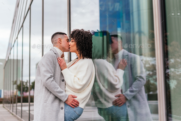 Beautiful view of a mixed woman with curly hair leaning on glass wall ...
