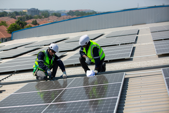 Solar panel installer installing solar panels on roof of warehouse ...