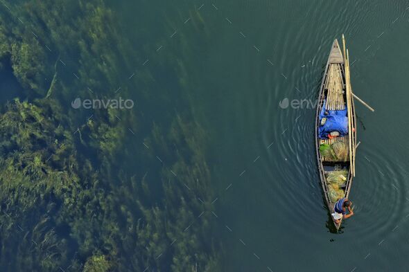 Bird's eye view of a fisherman rowing a small wooden boat on the ...