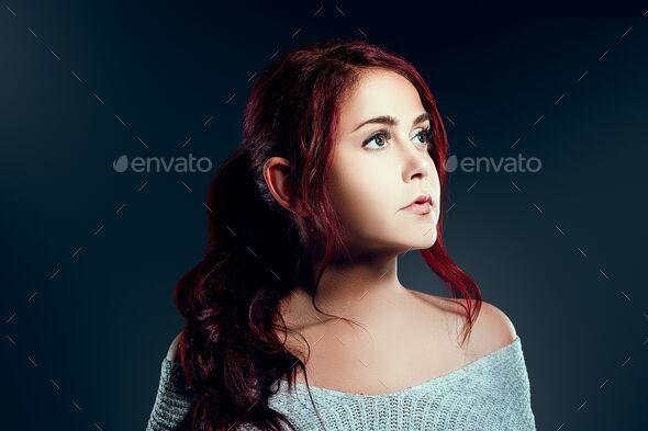 Sensual red haired woman in studio looking up to right side with ...