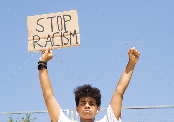 Afro teenage boy with a sign in his hands with the slogan: stop racism ...