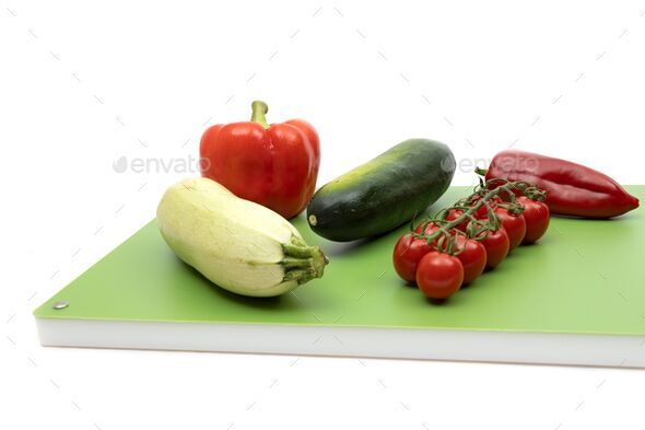 Vegetables on green professional chopping board on white background ...