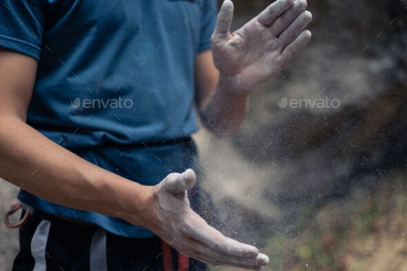 Shallow focus of a hiker chalking his hands for climbing a mountain in ...