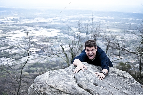 Male clinging on the rock at the moment of achieving the top Stock ...
