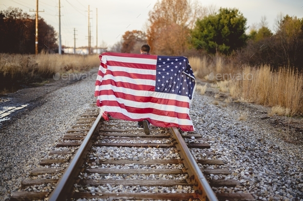 Male holding the united states flag behind him and walking on train ...