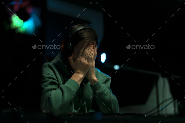 Stressed male cybersport gamer playing video game and praying with hope ...