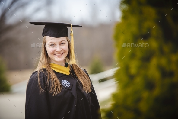Young attractive smiling blonde female wearing graduation gown on her ...