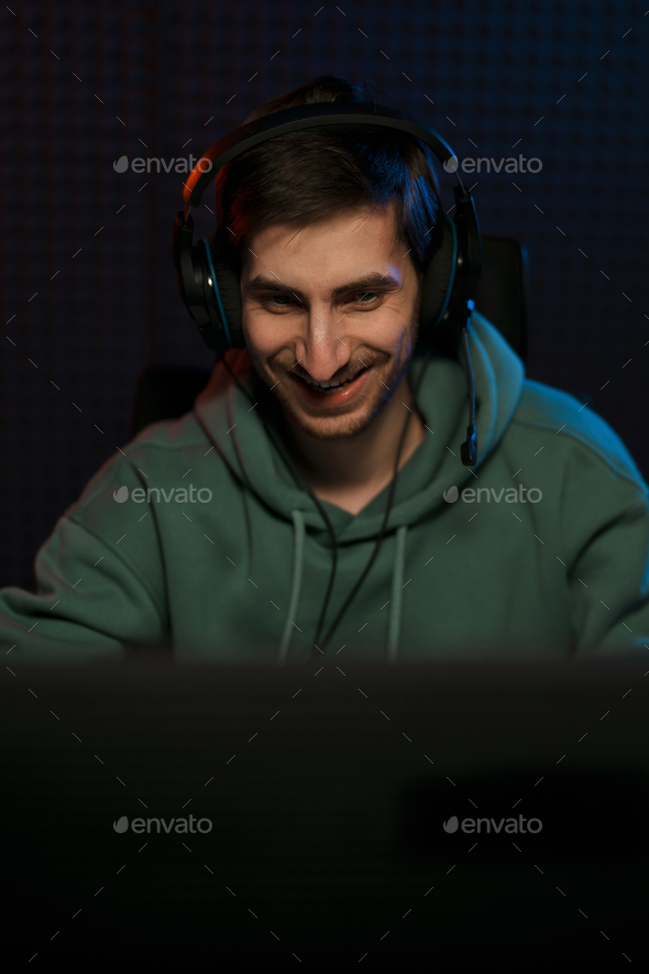 Cheerful male cybersport gamer sitting with hands behind head after ...