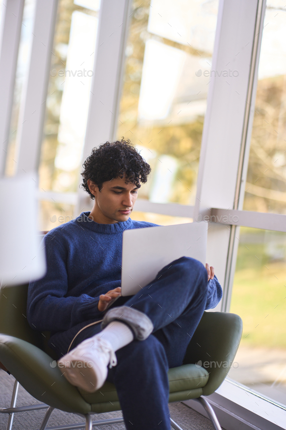 Young Latin American man, working remotely on laptop, telecommuting ...