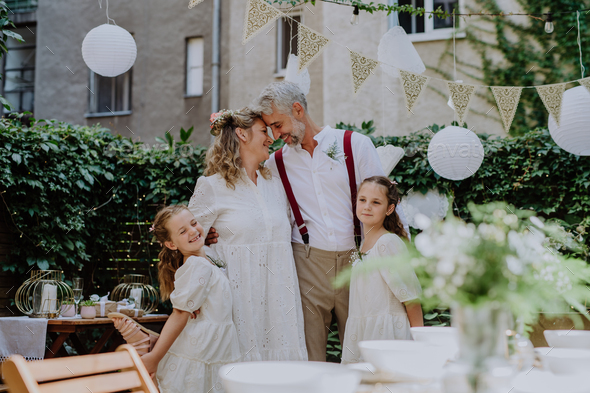 Mature bride and groom posing with their daughters at wedding reception ...