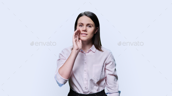 Young woman telling secret, holding her hands near her lips, on white ...