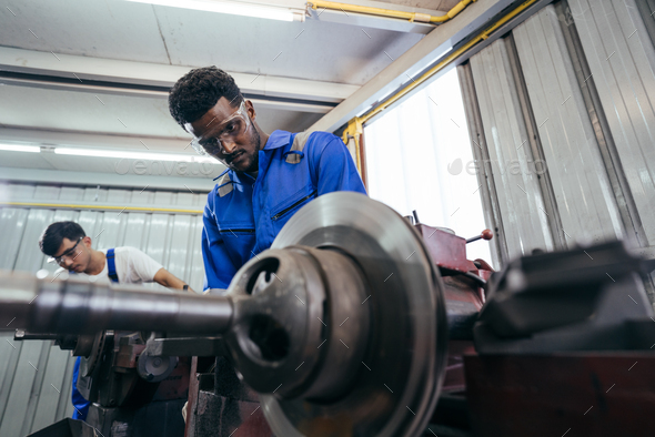 Diversity mechanic worker using metal lathe machine repairing at auto ...