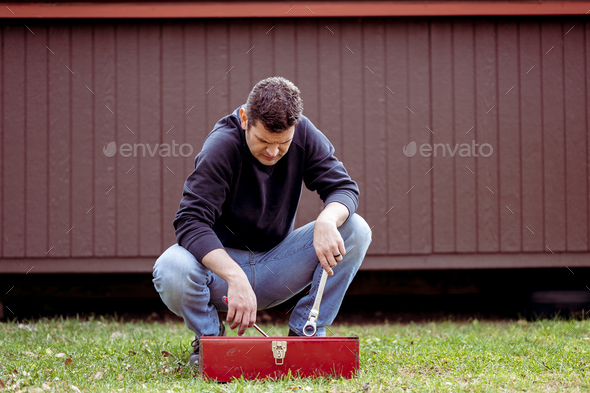 Male mechanic grabbing some tools from a toolb Stock Photo by wirestock