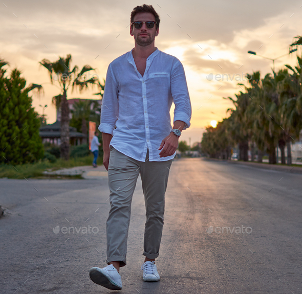 Male model walking down the street on background of sunset Stock Photo ...