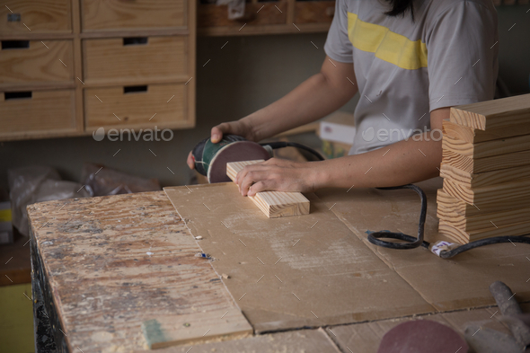 Closeup of a carpenter polishing wood lumber in the workshop with a ...