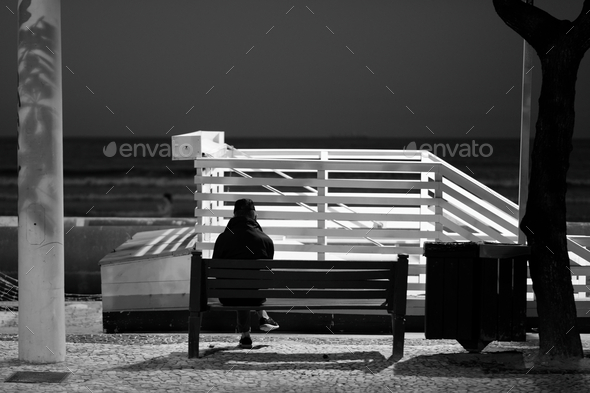 Grayscale scenic view of a person sitting on a bench from behind in ...