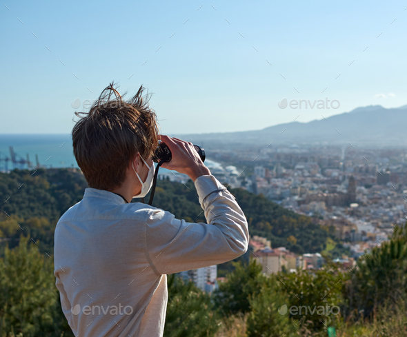 Spanish adventurous male traveler wearing a mask using binoculars and ...