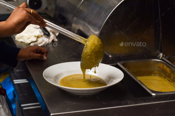 Restaurant kitchen employee pouring soup into a bowl Stock Photo by ...