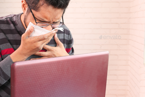 young asian man coughing and sneezes while working on laptop with copy ...