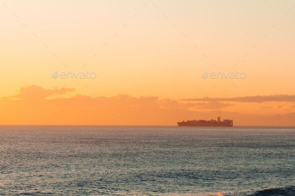 Ship on the horizon of sea at scenic sunset Stock Photo by wirestock