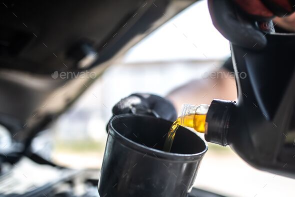 Car maintenance, service man changing motor oil in a modern passenger ...