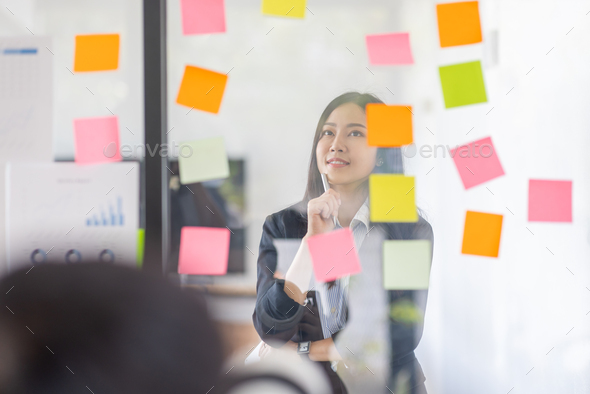Young Serious Asian Creative team use post it notes to share idea ...