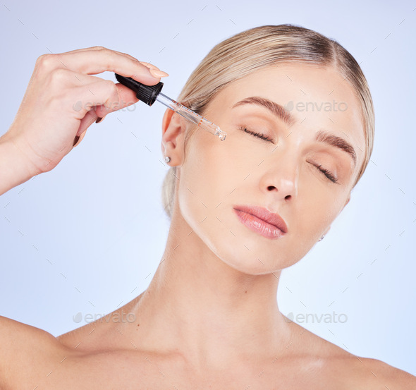 Face, eyes closed and skincare of woman with serum in studio isolated ...