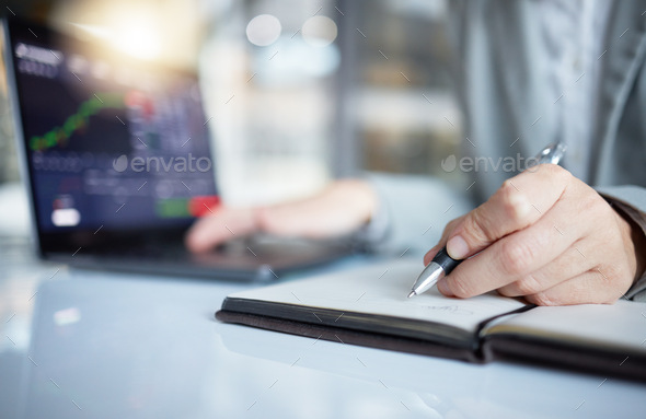 Trader, hands and writing notes in book by laptop on stock market chart ...